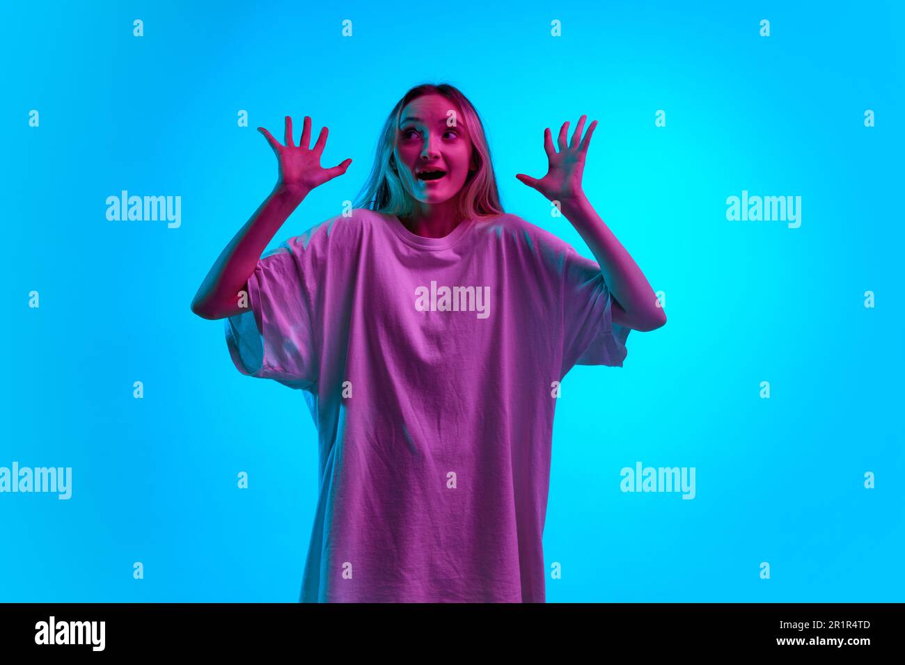 Portrait of frightened, young girl holding hands up with open mouth ...