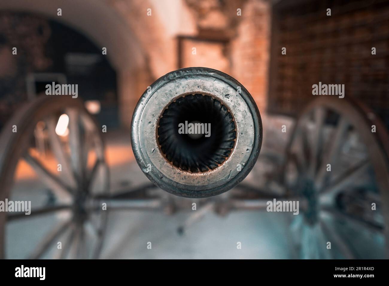 An antique metal cannon placed next to a brick wall with its ...