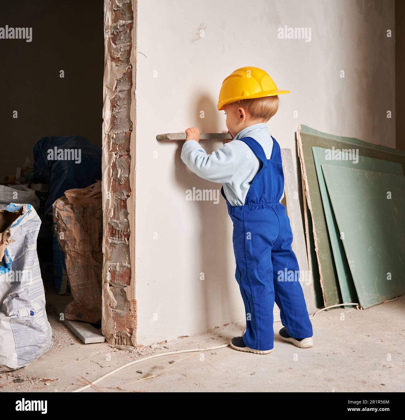 Child construction worker holding spirit level instrument. Kid in ...