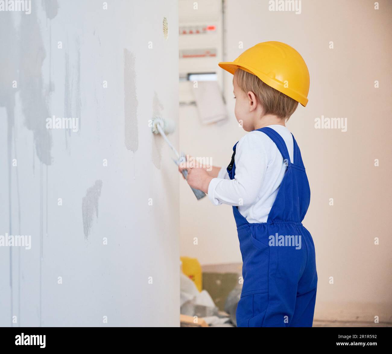 Child construction worker painting wall in apartment under renovation ...