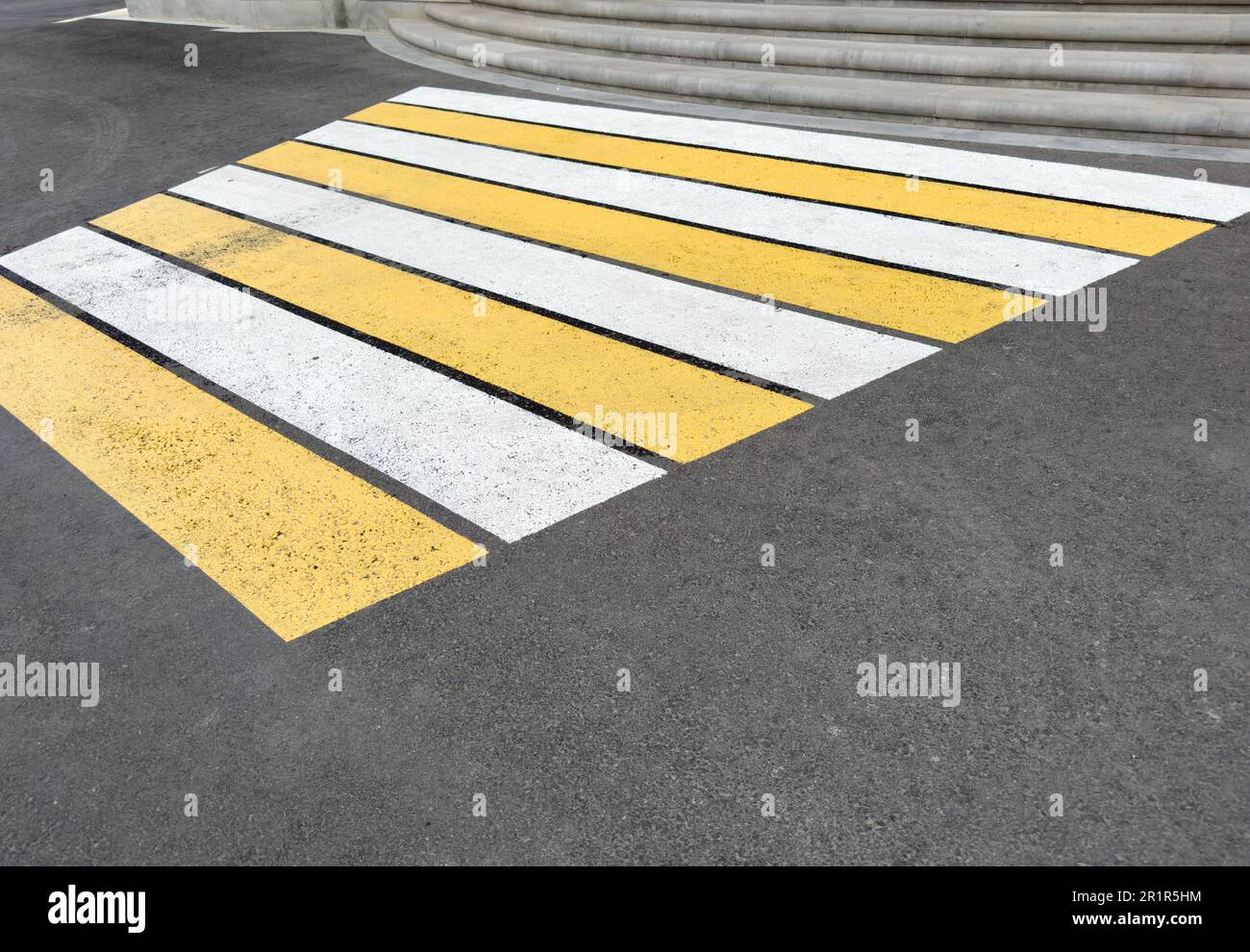 Yellow pedestrian crosswalk across the road with asphalt pavement ...