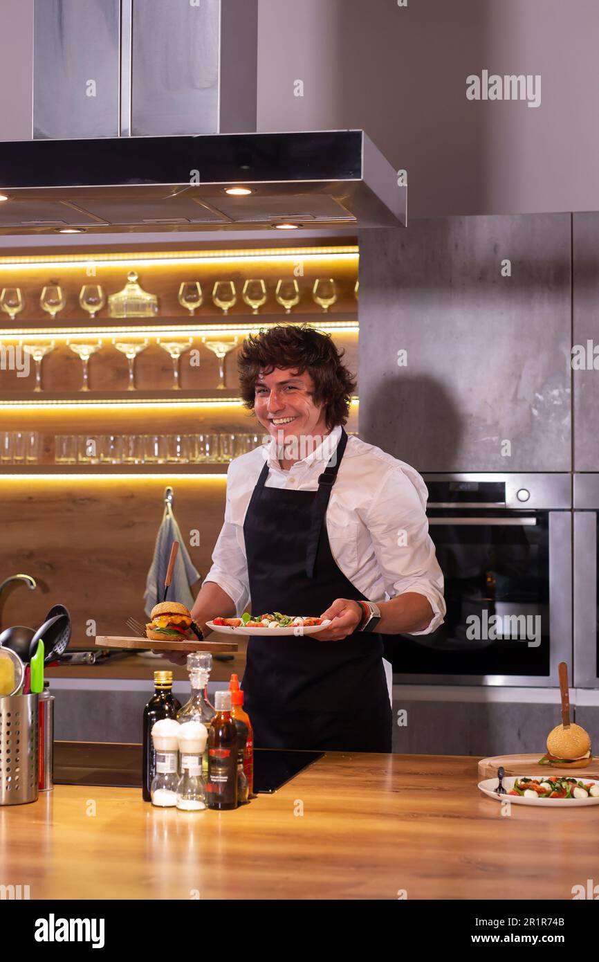 Portrait happy chef with cooked meals for a dinner party in the kitchen ...