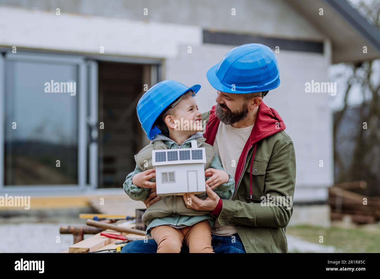 Father and his little son in front of their unfinished house holding ...