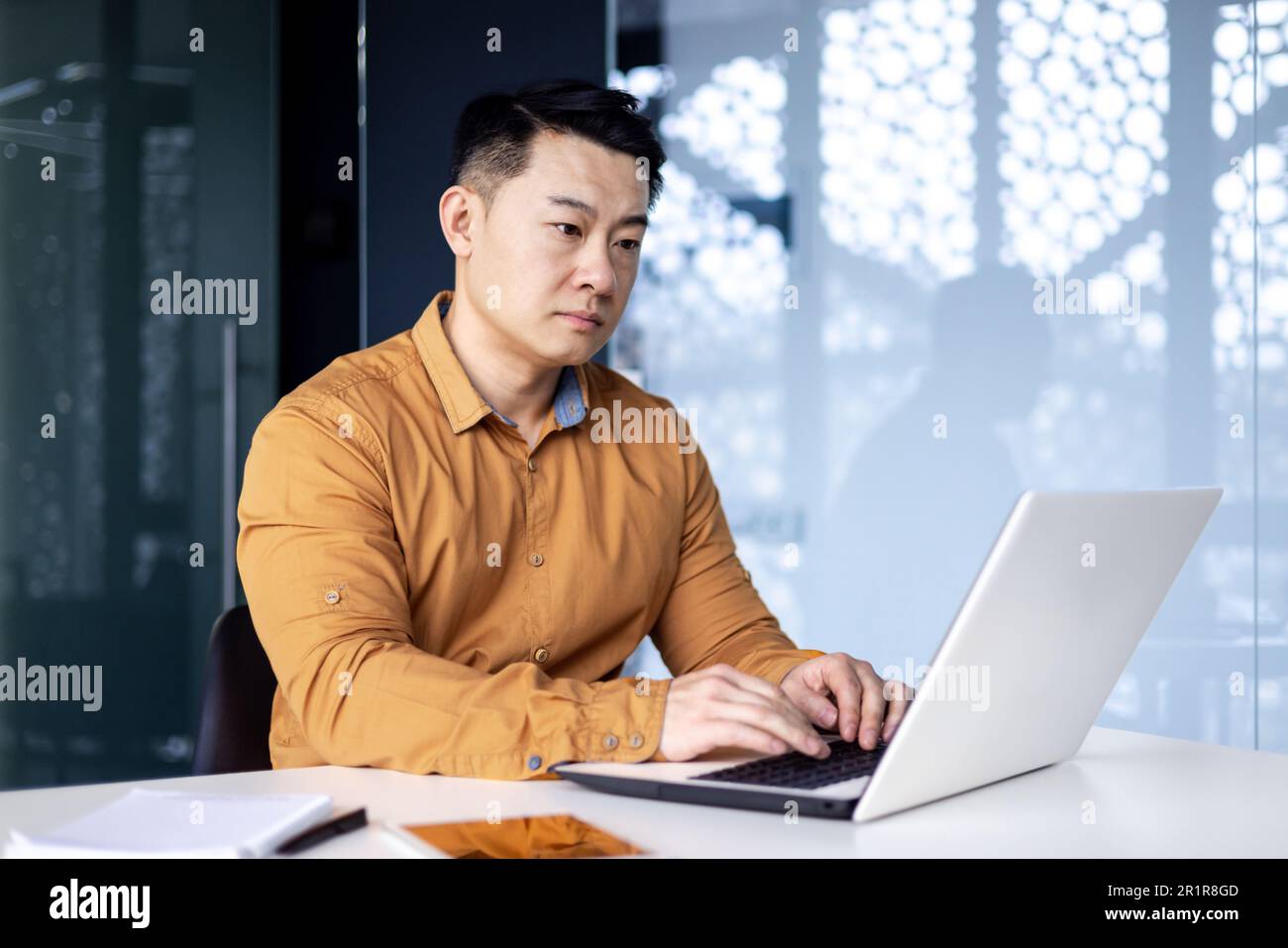Serious and thoughtful young man of Asian origin programmer, developer works in office at ...