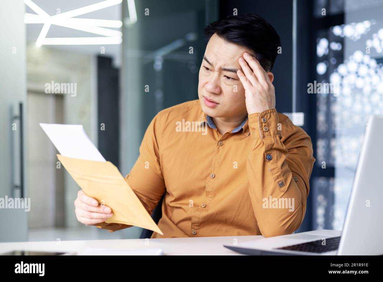 Serious and upset asian businessman reading letter with bad news ...