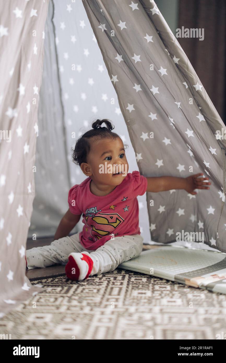 Baby girl from interracial marriage plays inside of tent in room ...
