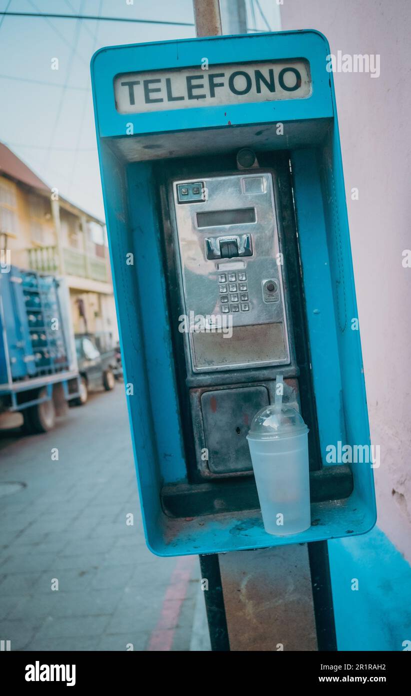 An old-style, retro payphone in front of a pink building in Guatemala ...