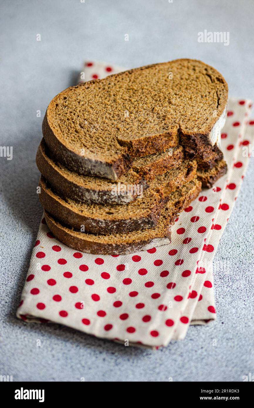 Overhead view of a stack of dark sourdough rye bread slices on a folded ...