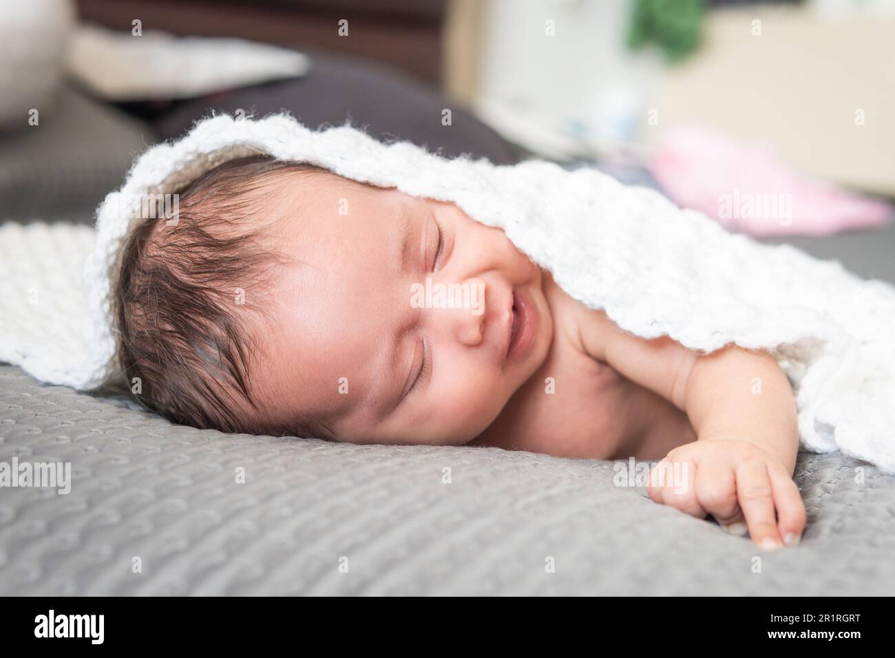 Happy Latina baby sleeping smiling on a bed covered with a white ...
