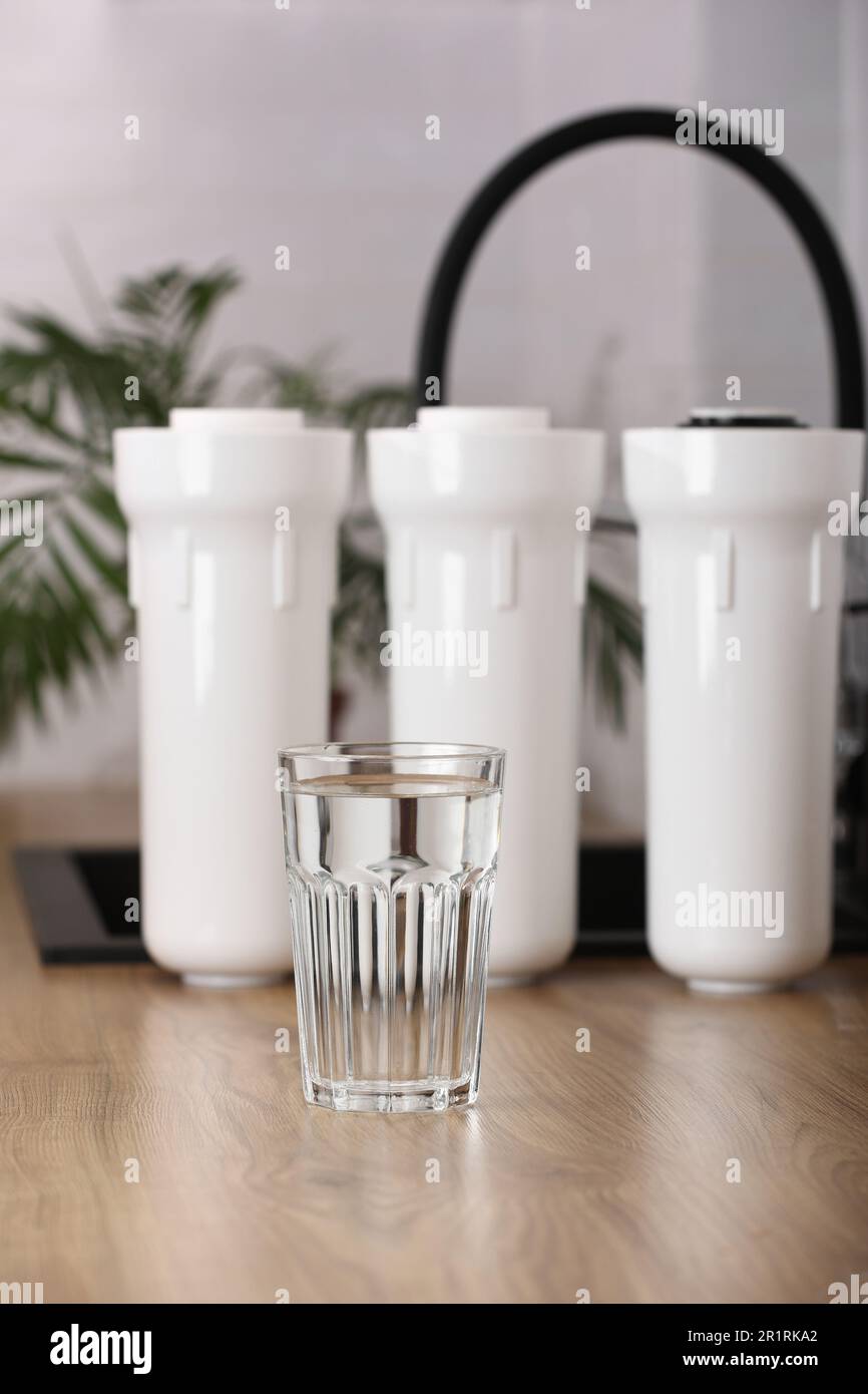 Glass of clean drinkable water and set of filter cartridges on wooden ...