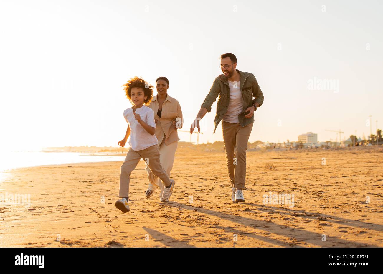 Beach fun. Happy diverse family walking and fooling by the seaside, boy ...