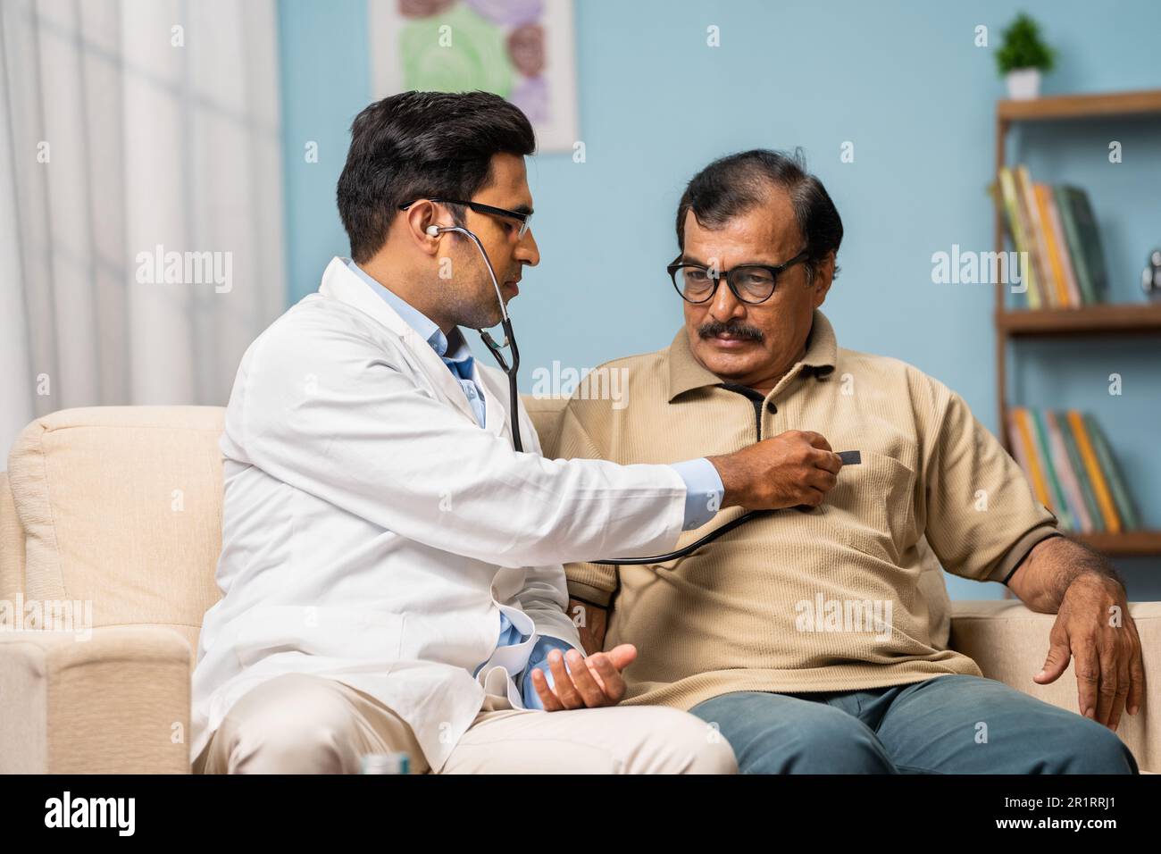 Indian doctor examining sick senior man by using stethoscope while ...
