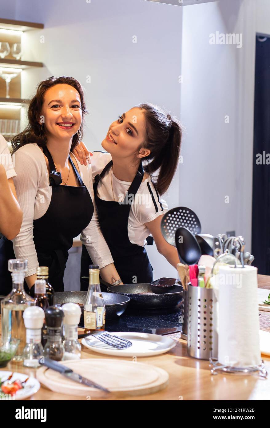 Two funny professional female chefs cooking food in large kitchen and ...