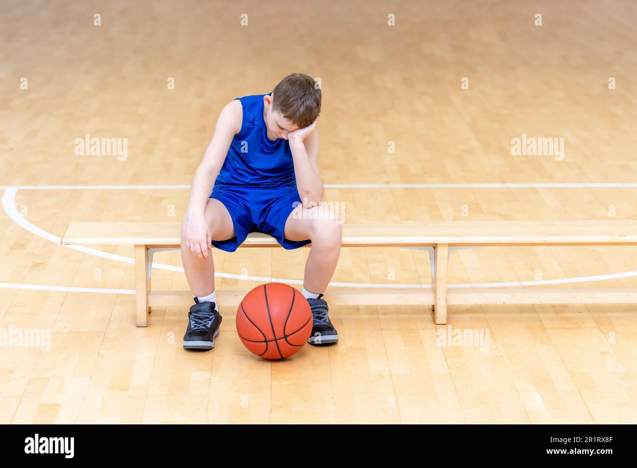 Sad disappointed boy with basketball ball in a physical education ...