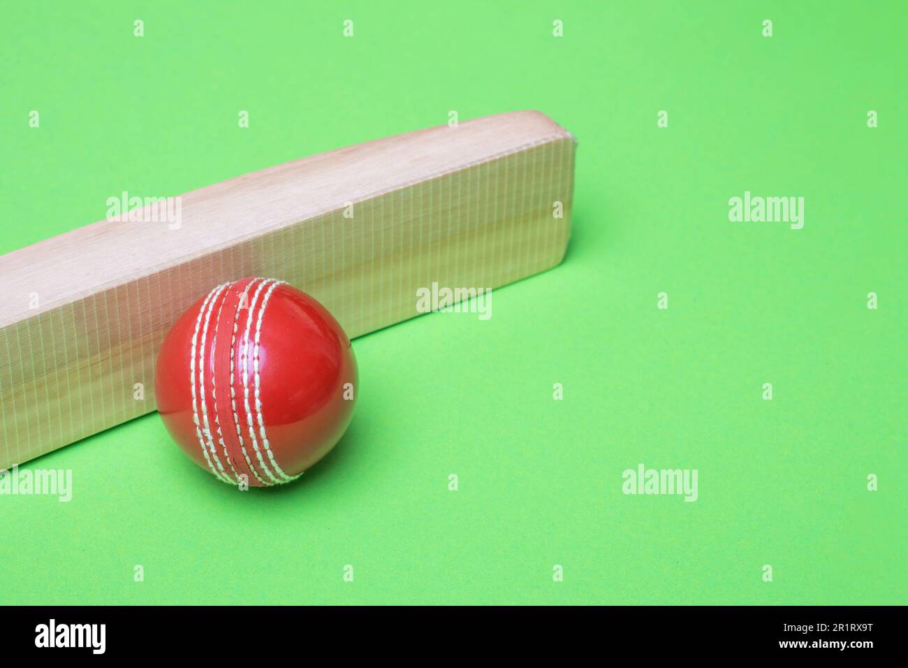 Cricket bat and red balls on green background. Horizontal sport theme ...