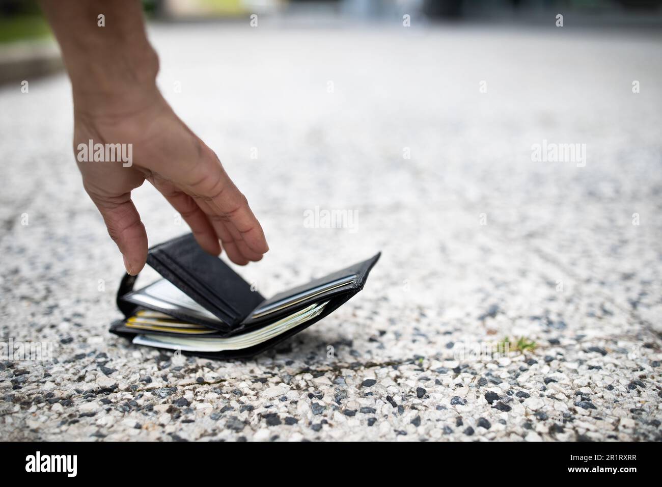 Closeup view of black man picking up lost wallet full of money ...