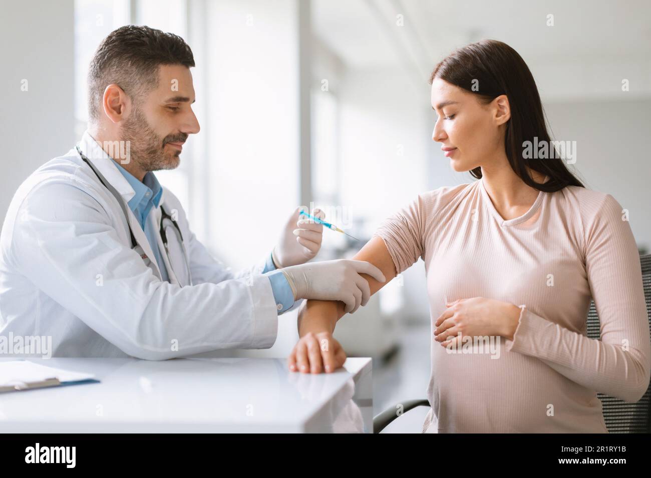 Injection against virus for risk groups. Male doctor making shot to ...