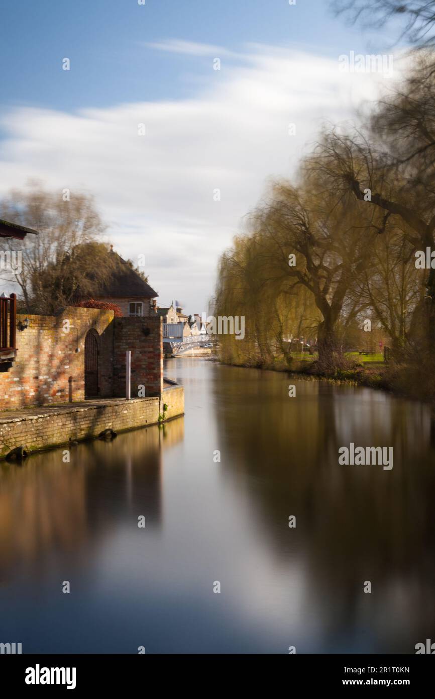 A peaceful still river with trees and buildings Stock Photo - Alamy