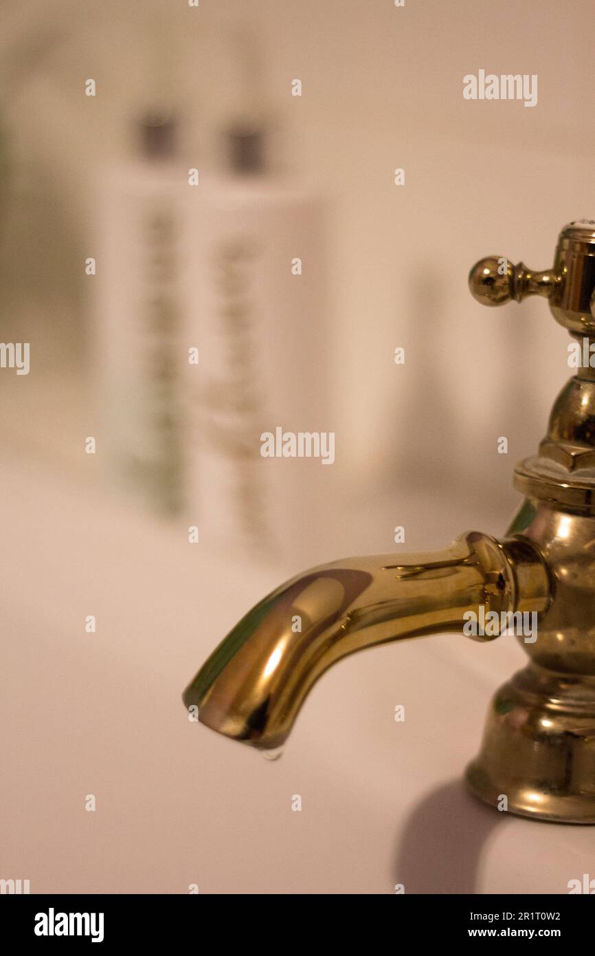 A set of brass traditional taps with some toiletries in the background ...