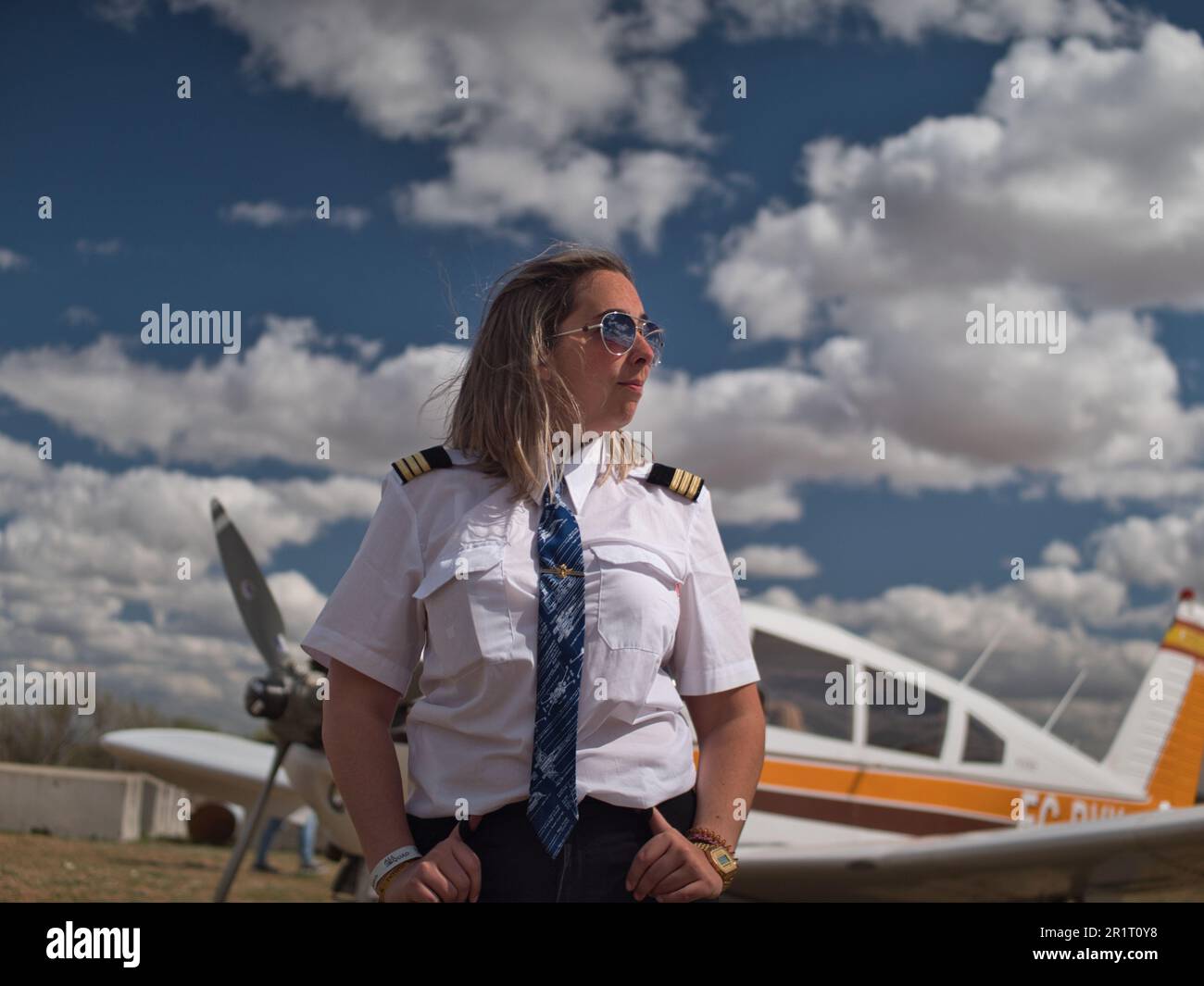 A blonde female pilot dressed in uniform posing near an airplane Stock ...