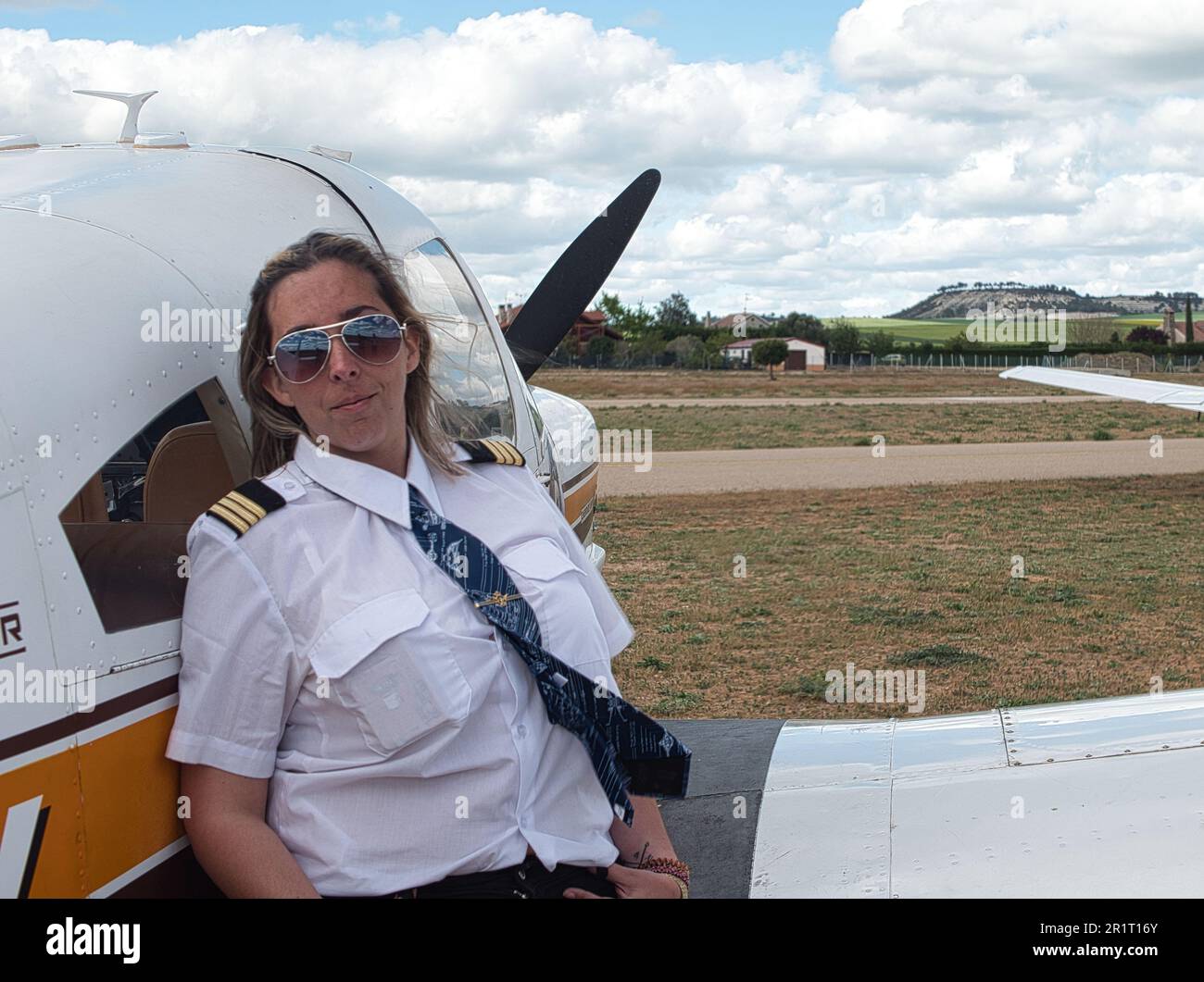 A blonde female pilot dressed in uniform posing near an airplane Stock ...
