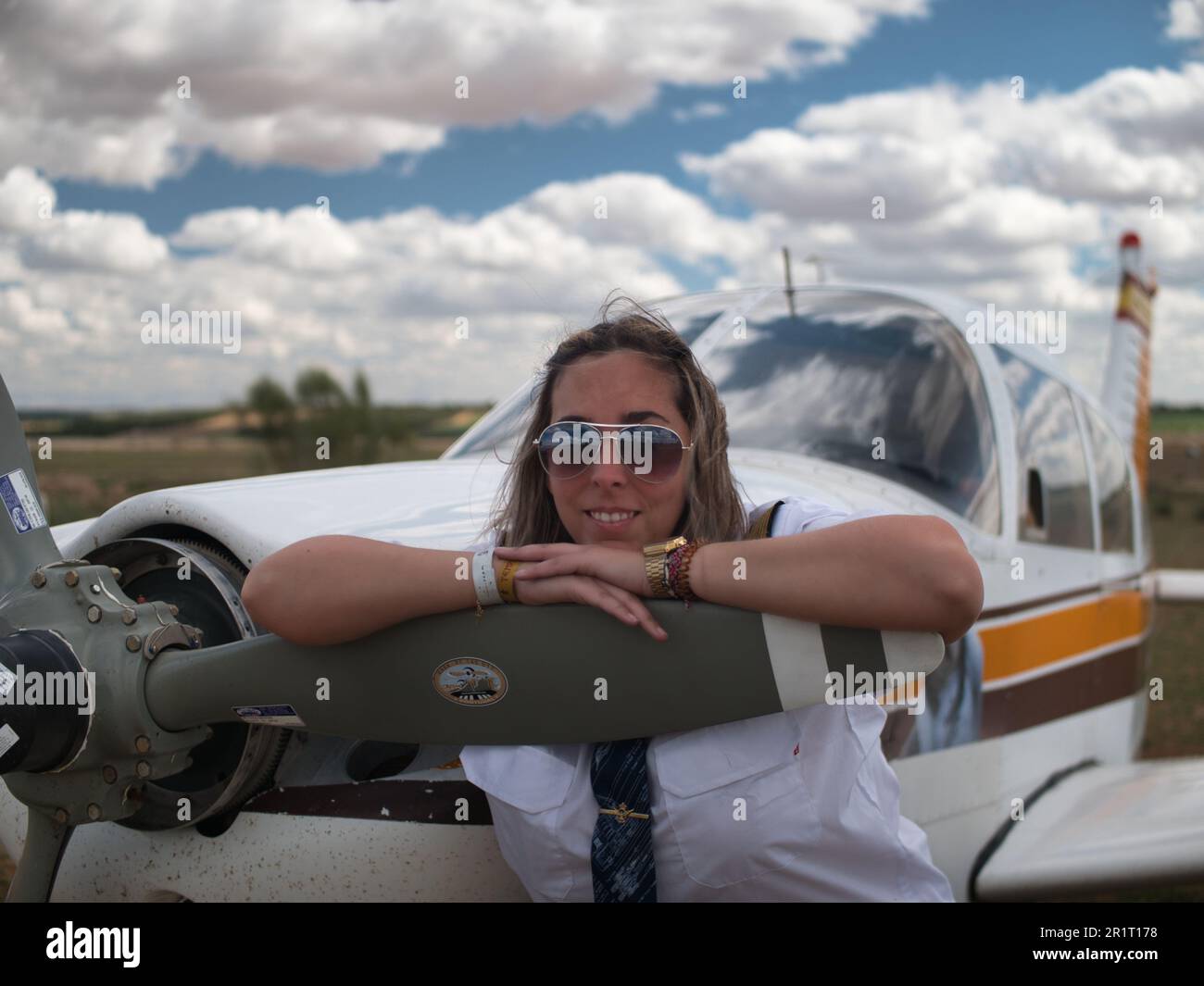A blonde female pilot dressed in uniform posing near an airplane Stock ...