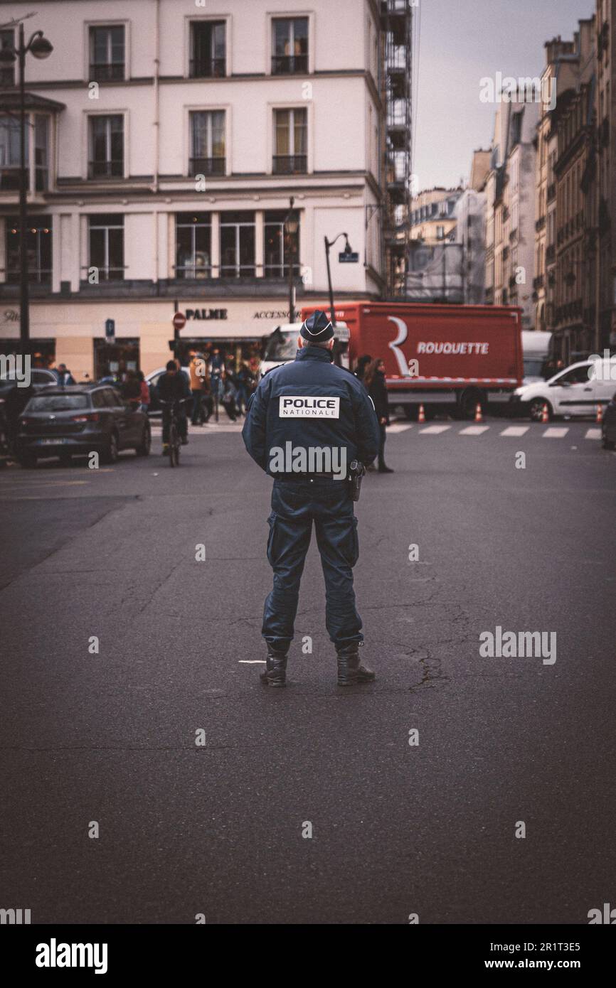 A vertical rear view of a policeman on the street during a protest riot ...