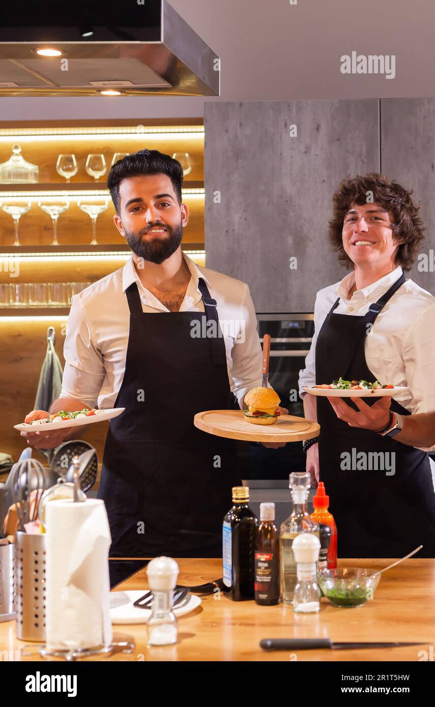 Portrait two happy chefs with cooked meals for a dinner party in the ...