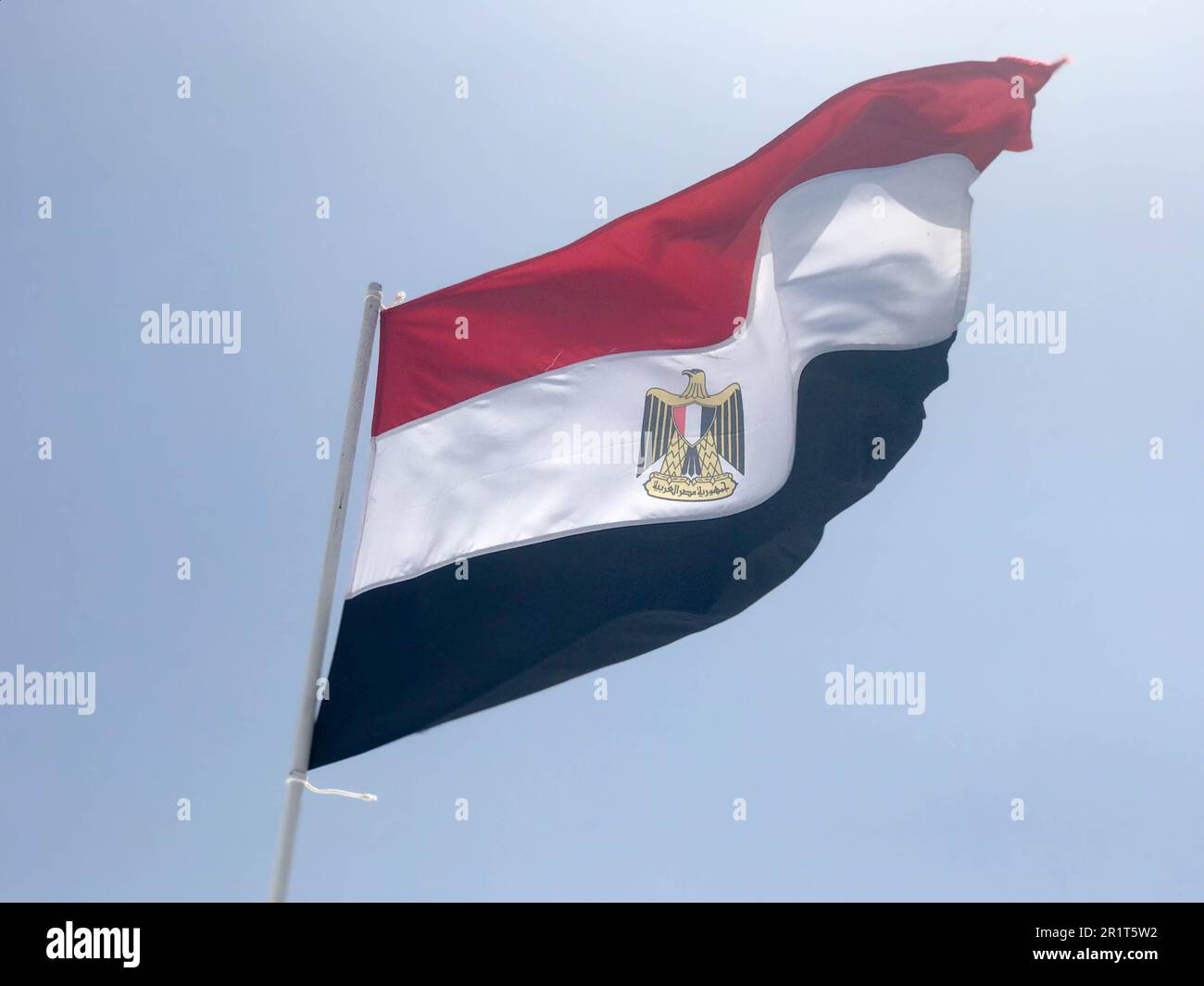 A large black and white striped Egyptian flag rising against the blue ...