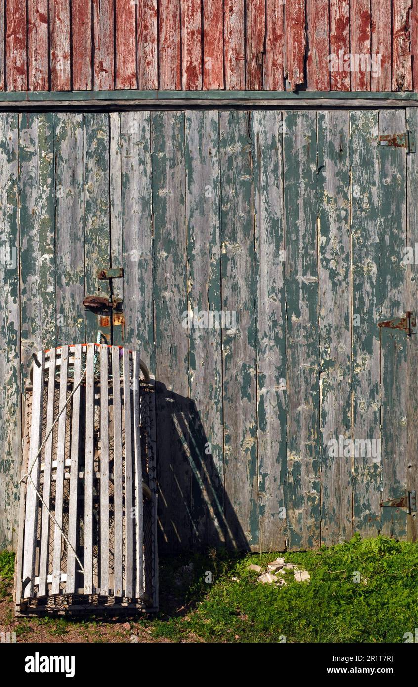 A wooden lobster trap leans against the faded door of a building in ...