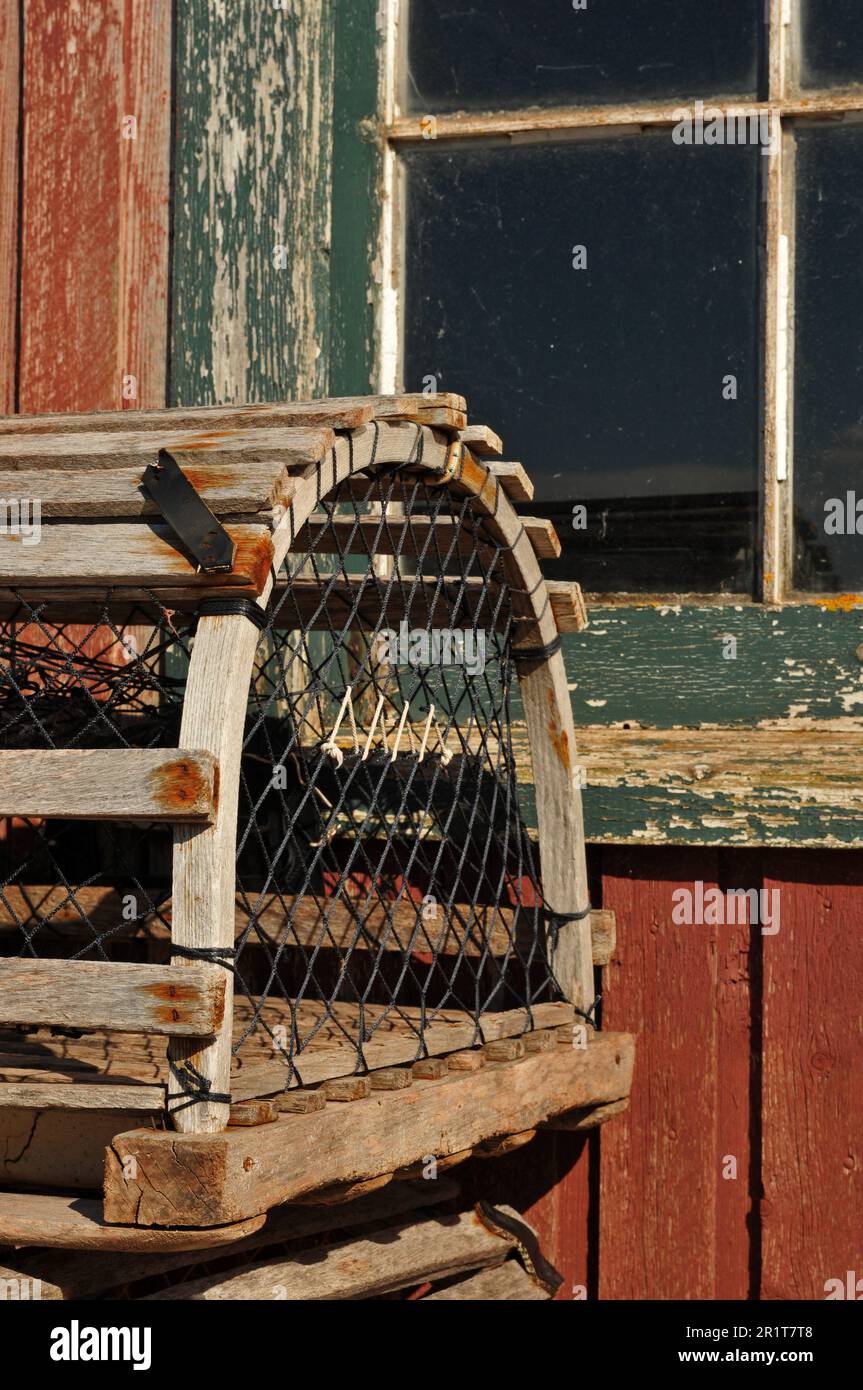 A traditional wooden lobster trap sits in front of a shed window in a ...
