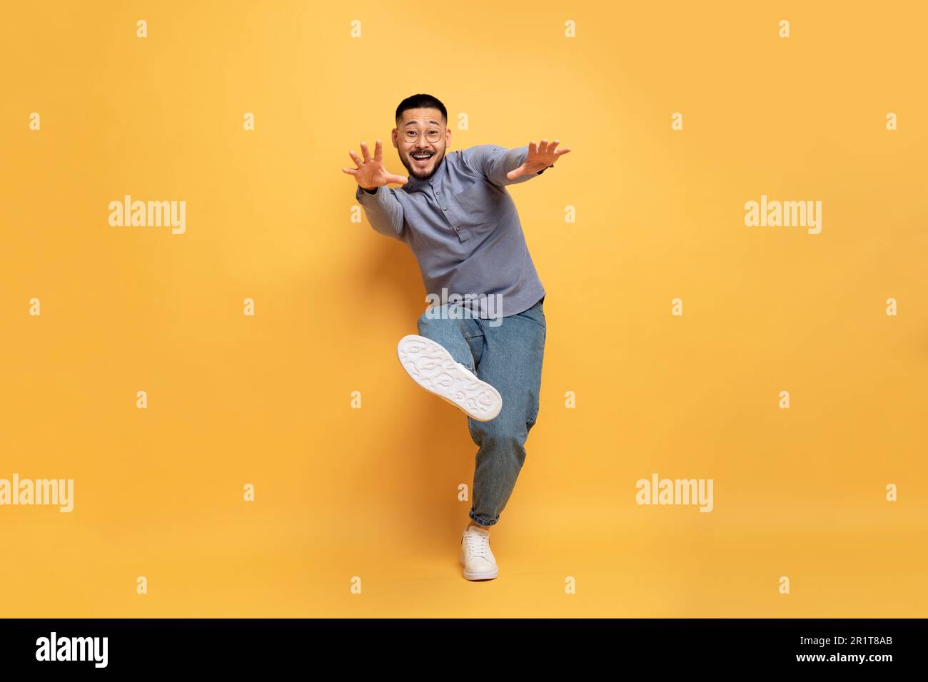 Cheerful young asian man having fun on yellow studio background Stock ...