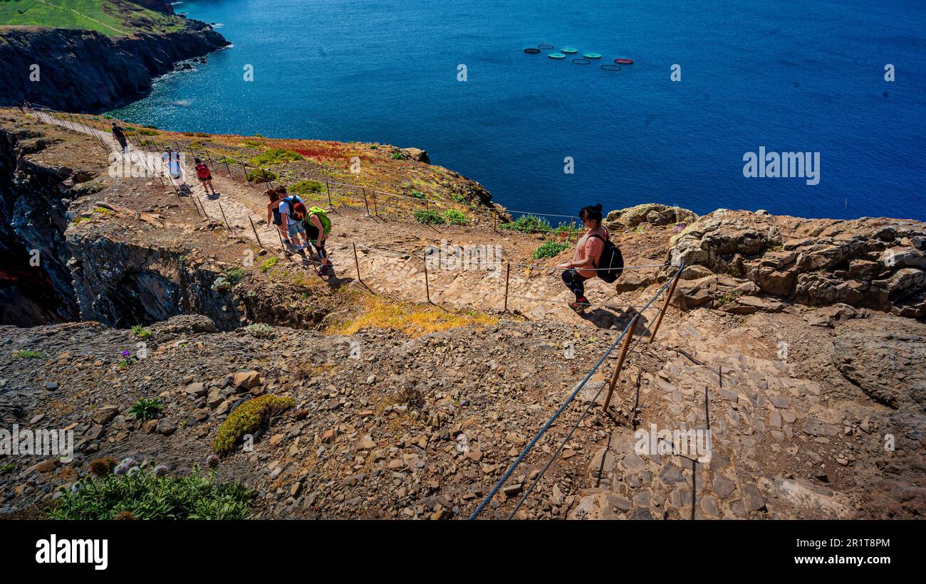A group of people walking along a rugged scenic pathway next to an ...