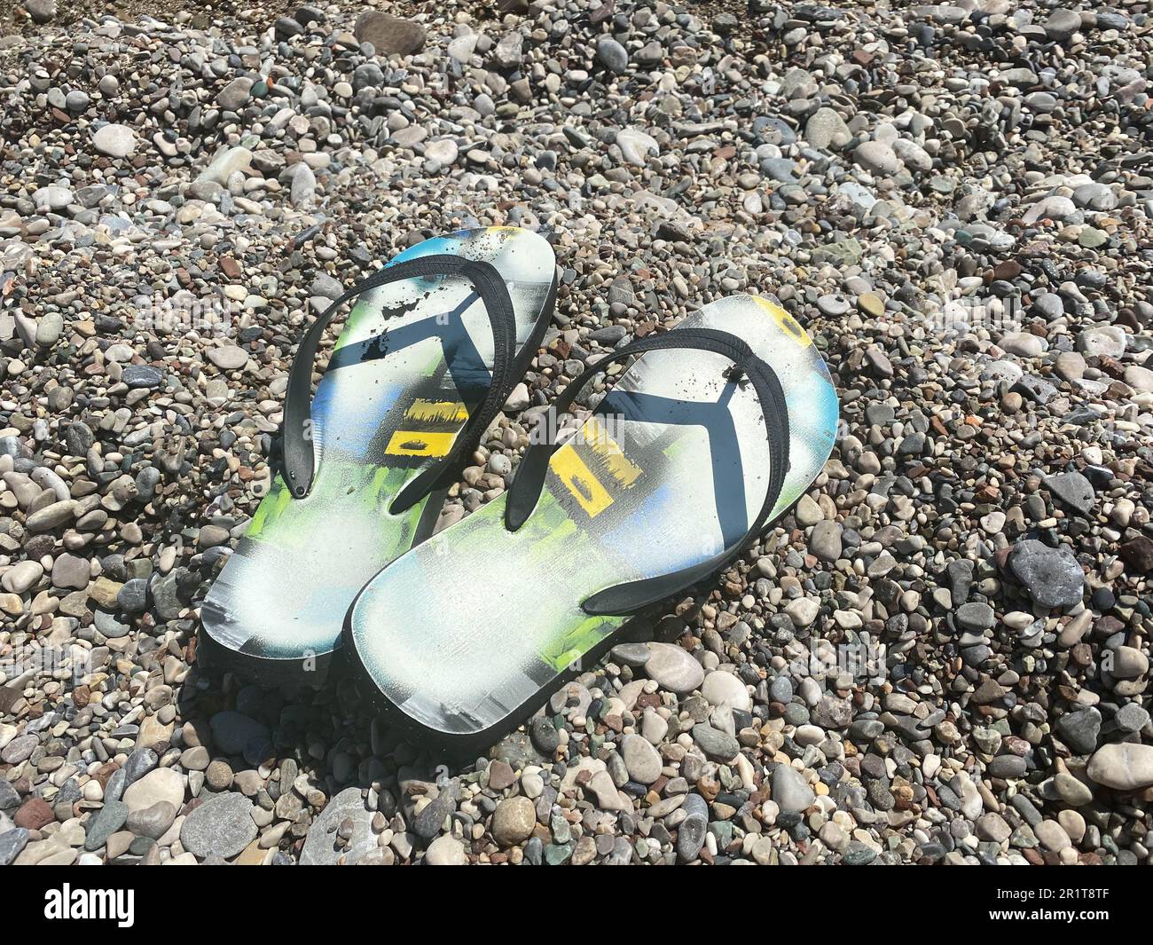 Beach scene with flip flop sandals lying on sea coquina shells and ...