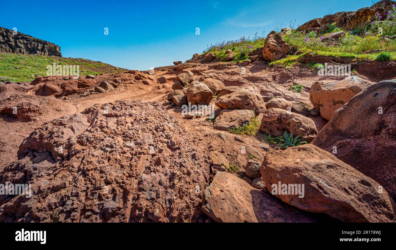 A dirt road lined with rocky, gravel-covered terrain extends into the ...