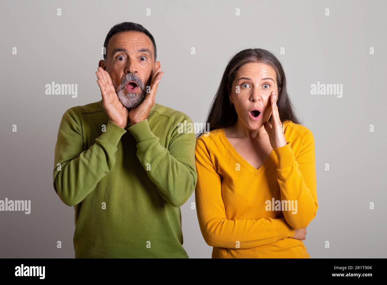 Shocked caucasian elderly man and wife with open mouth on gray studio ...
