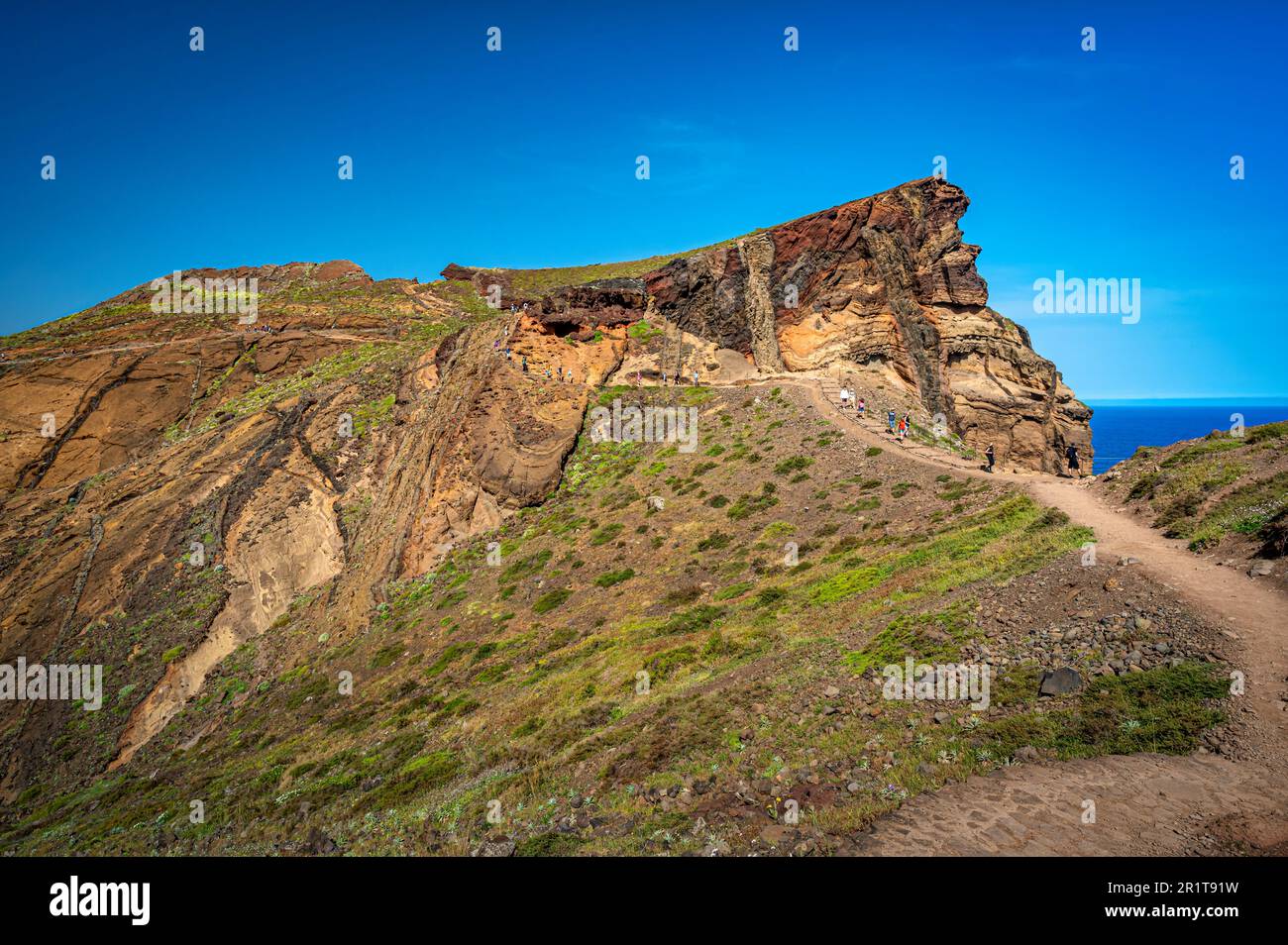A scenic coastal trail featuring a rocky cliff overlooking the vast ...