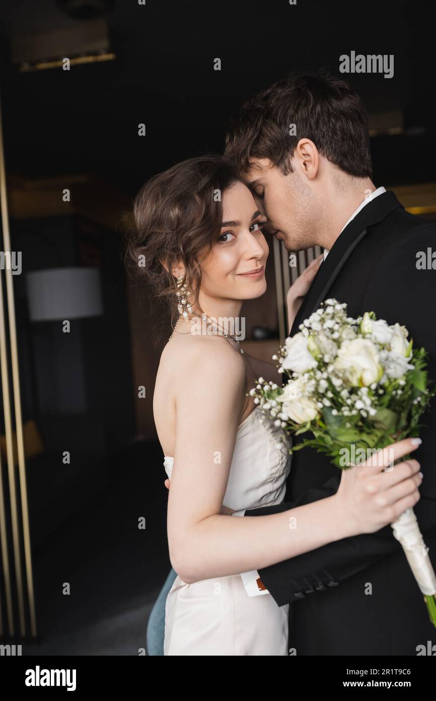brunette bride in elegant wedding dress holding bridal bouquet with ...
