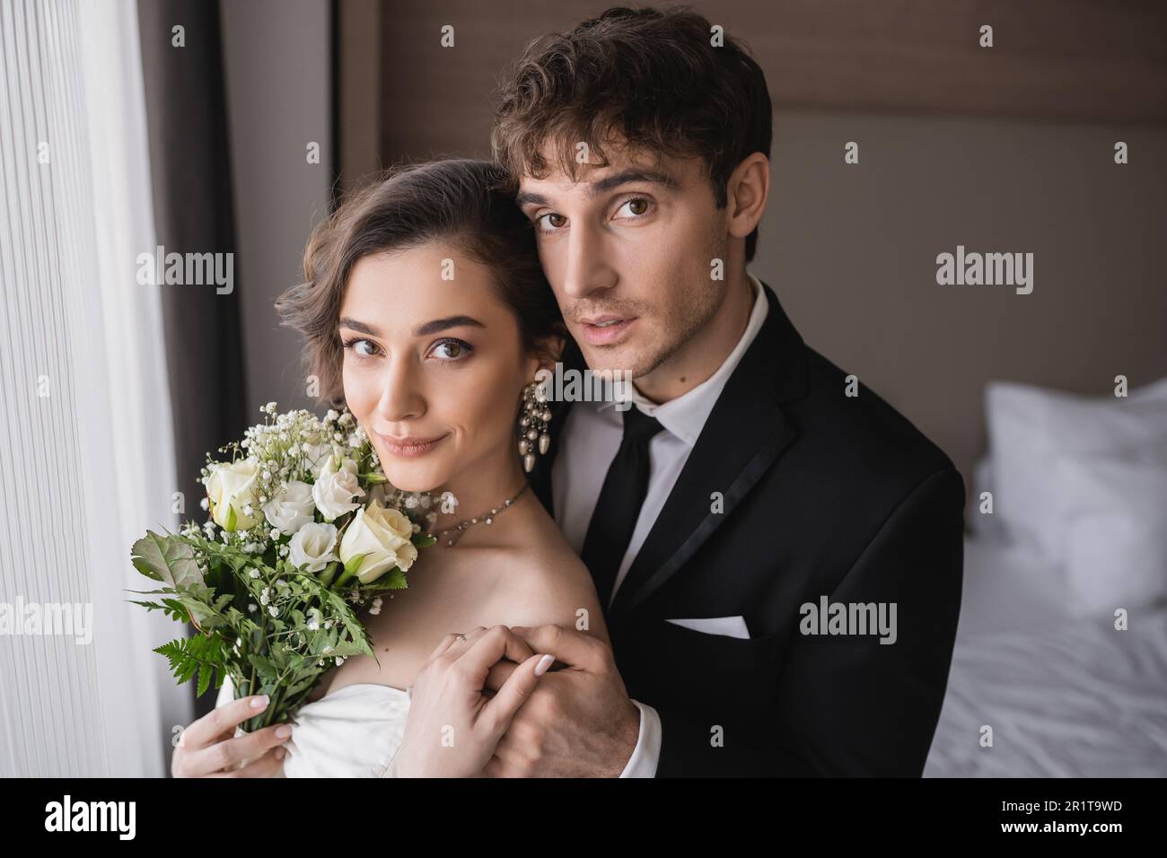pretty young bride in jewelry, white dress with bridal bouquet holding ...