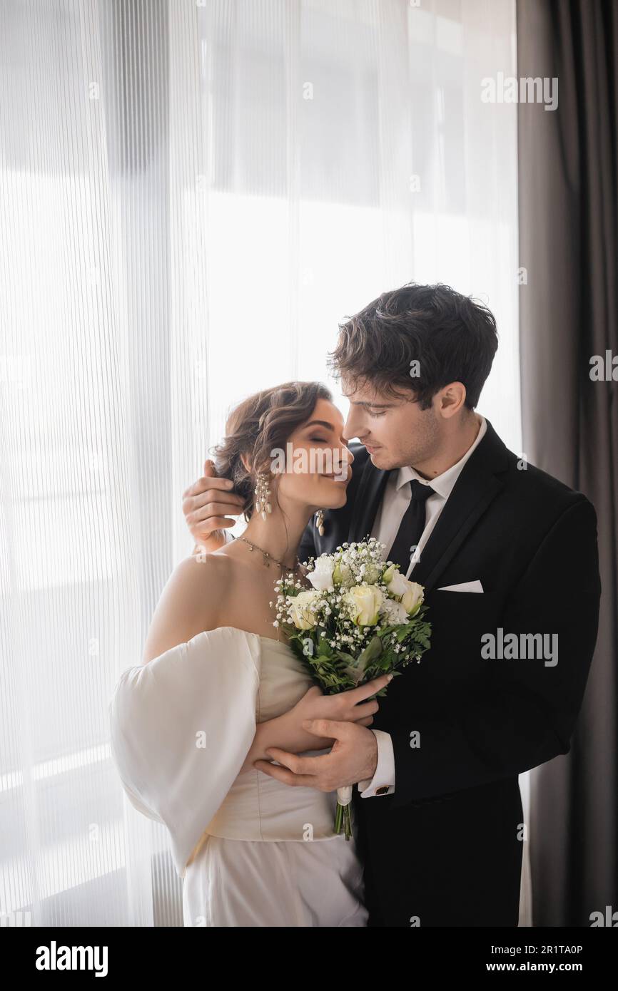 groom in classic formal wear hugging happy bride in jewelry, white ...