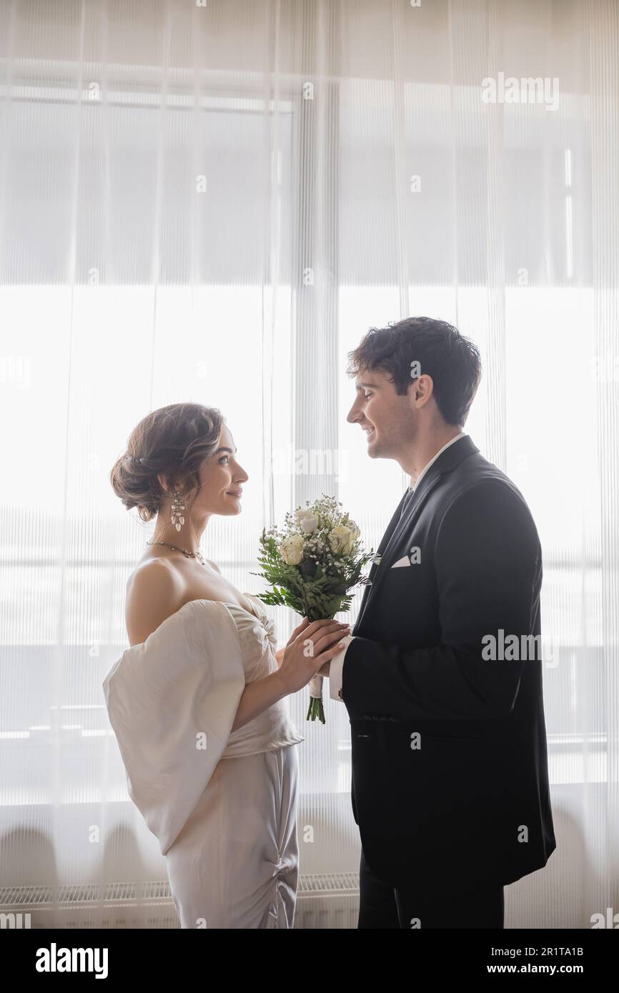 side view of bride in jewelry, white dress with bridal bouquet and ...