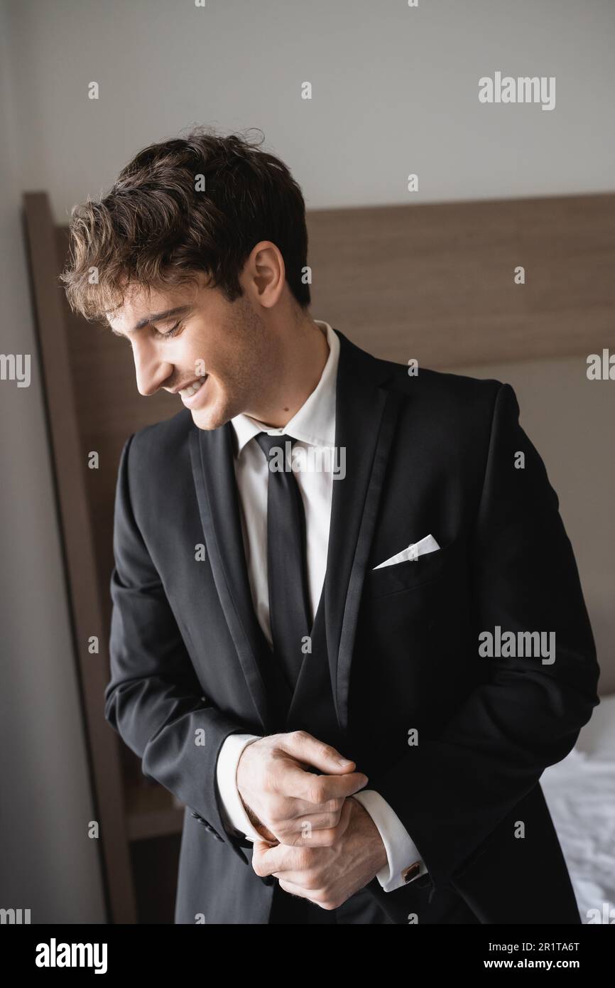 positive groom in formal wear with classy black tie and white shirt ...