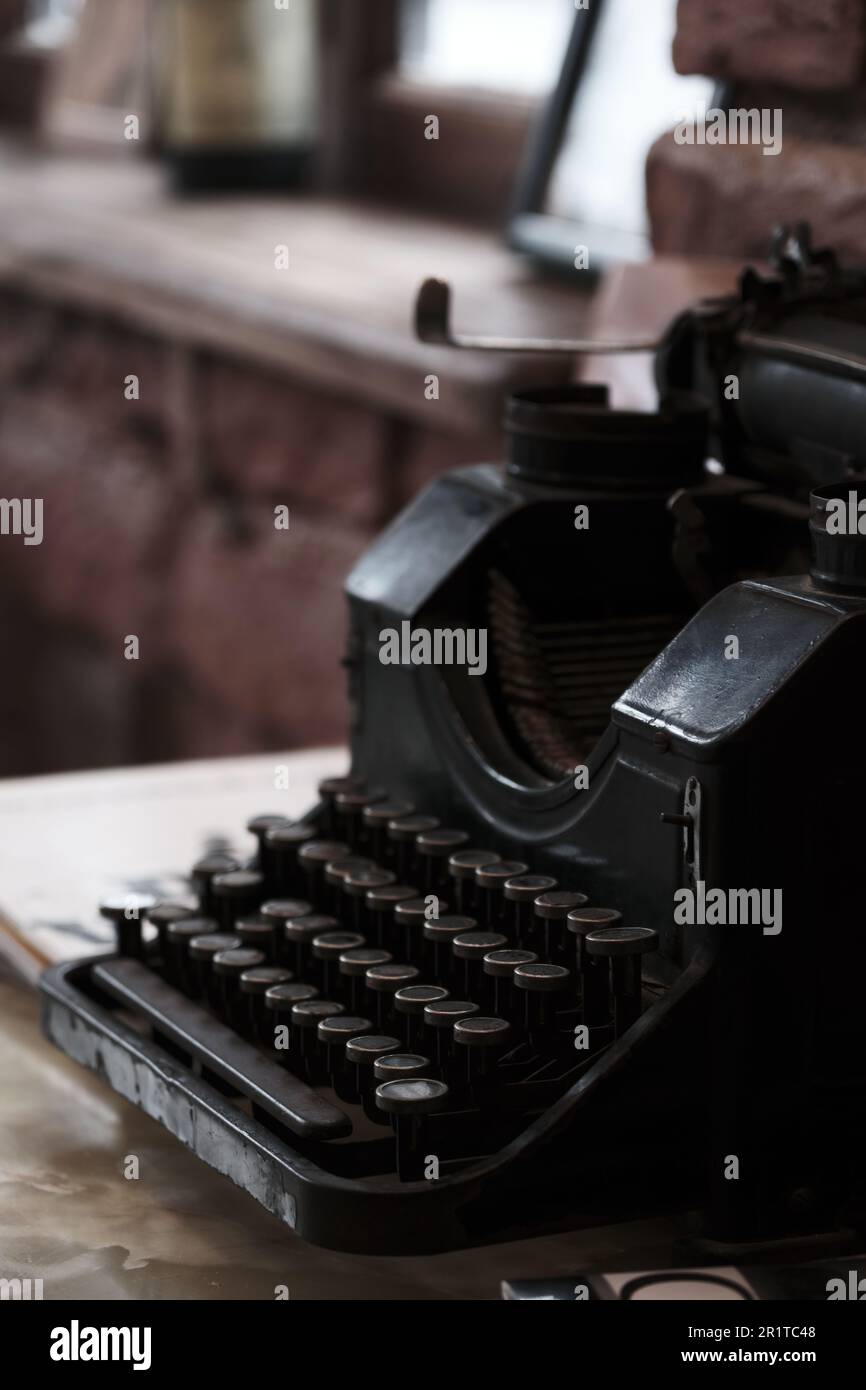 An antique typewriter displayed atop a wooden desk surrounded by ...