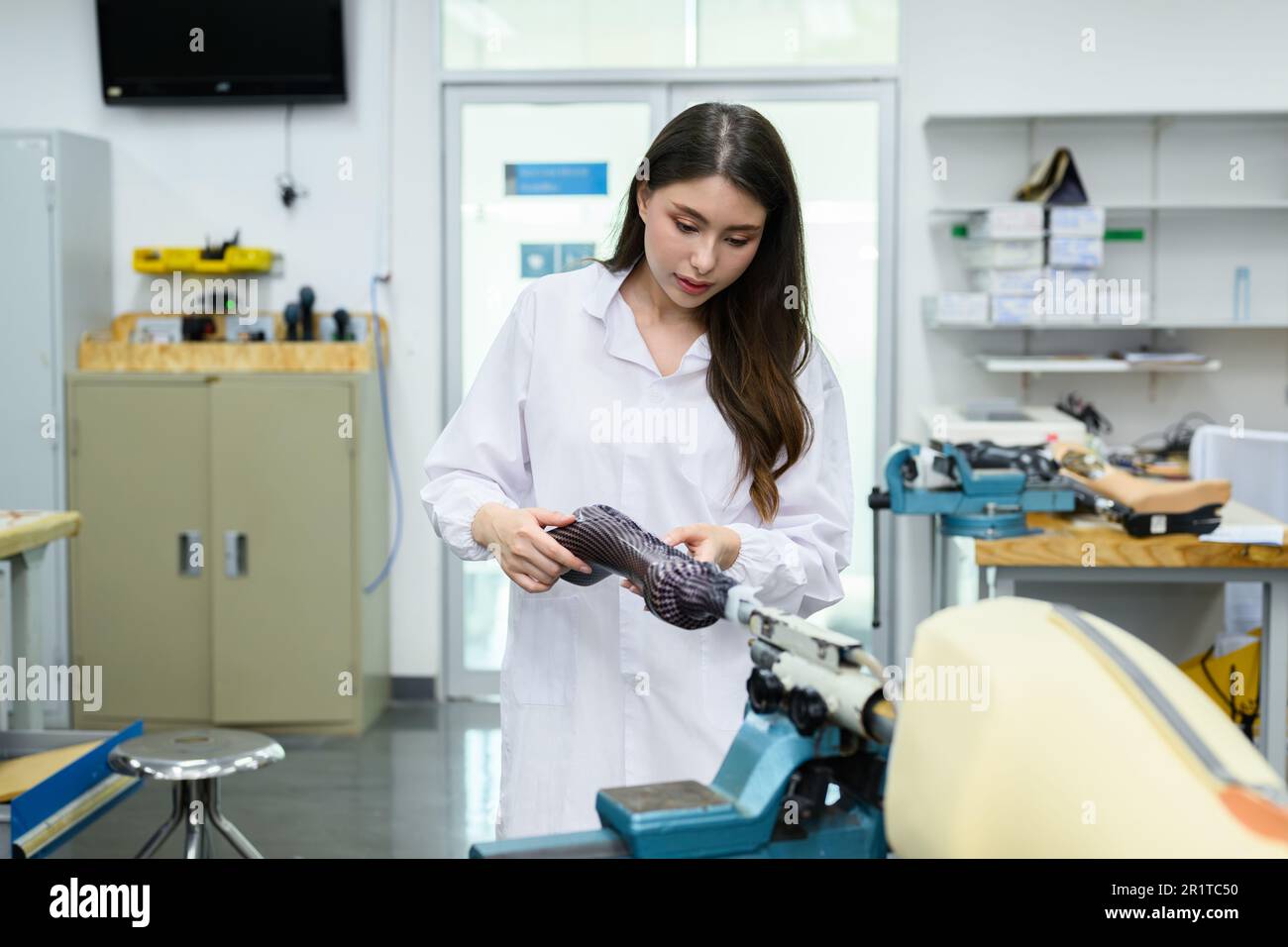 Female technician assembling and fixing parts of modern prosthetic leg ...