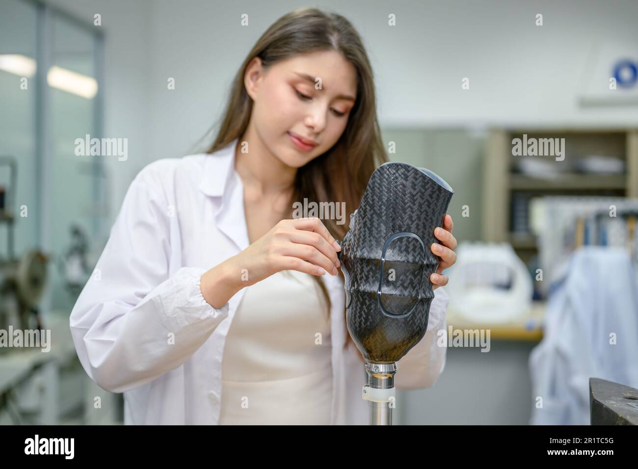Female technician assembling and fixing parts of modern prosthetic leg ...