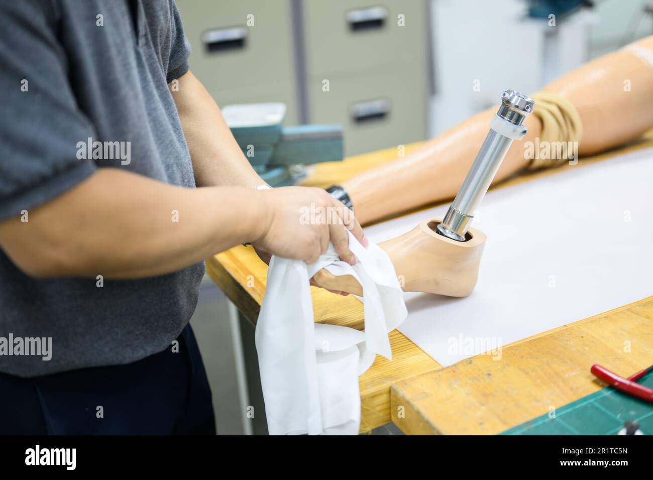 Male worker assembling parts of artificial leg in prosthetic workshop ...