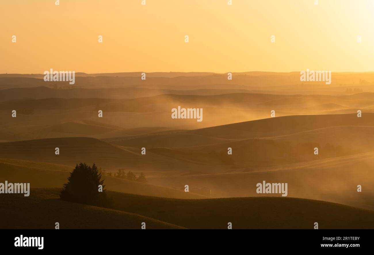 A stunning sunrise illuminates the horizon over a rolling landscape ...