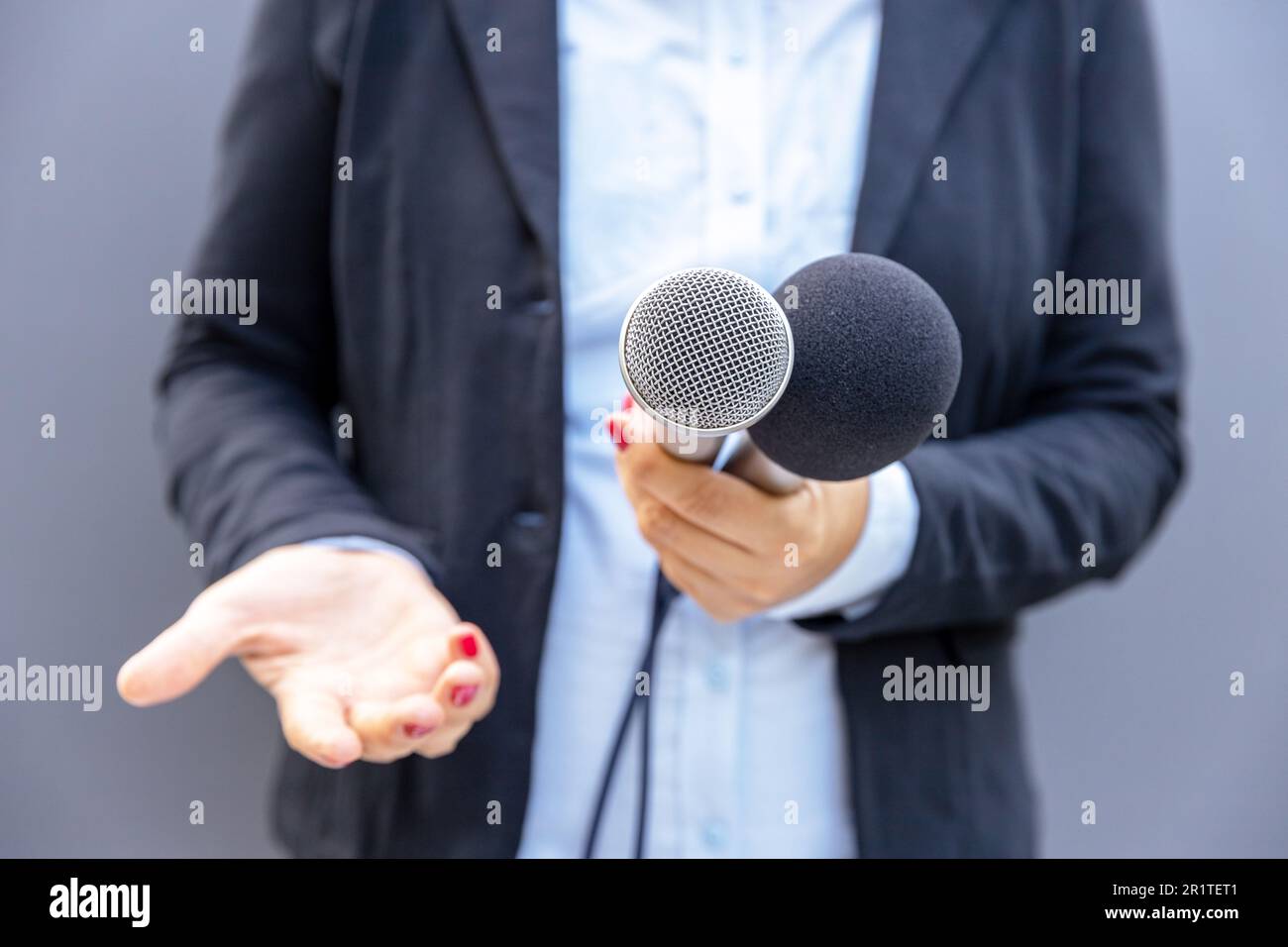 Female journalist holding microphone and gesturing during media interview. Freedom of the media ...