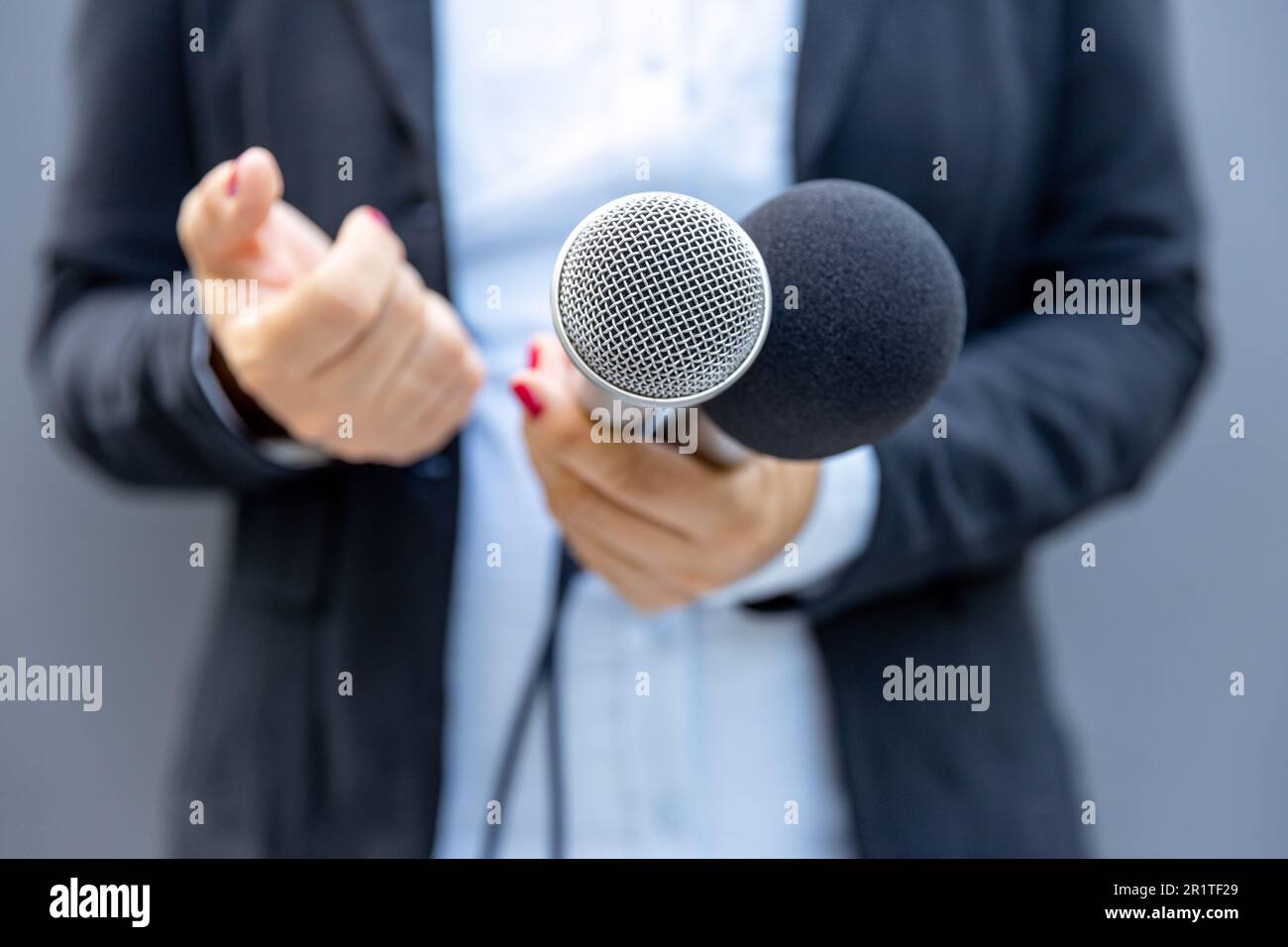 Female reporter holding microphone and gesturing during media interview. Freedom of the press ...
