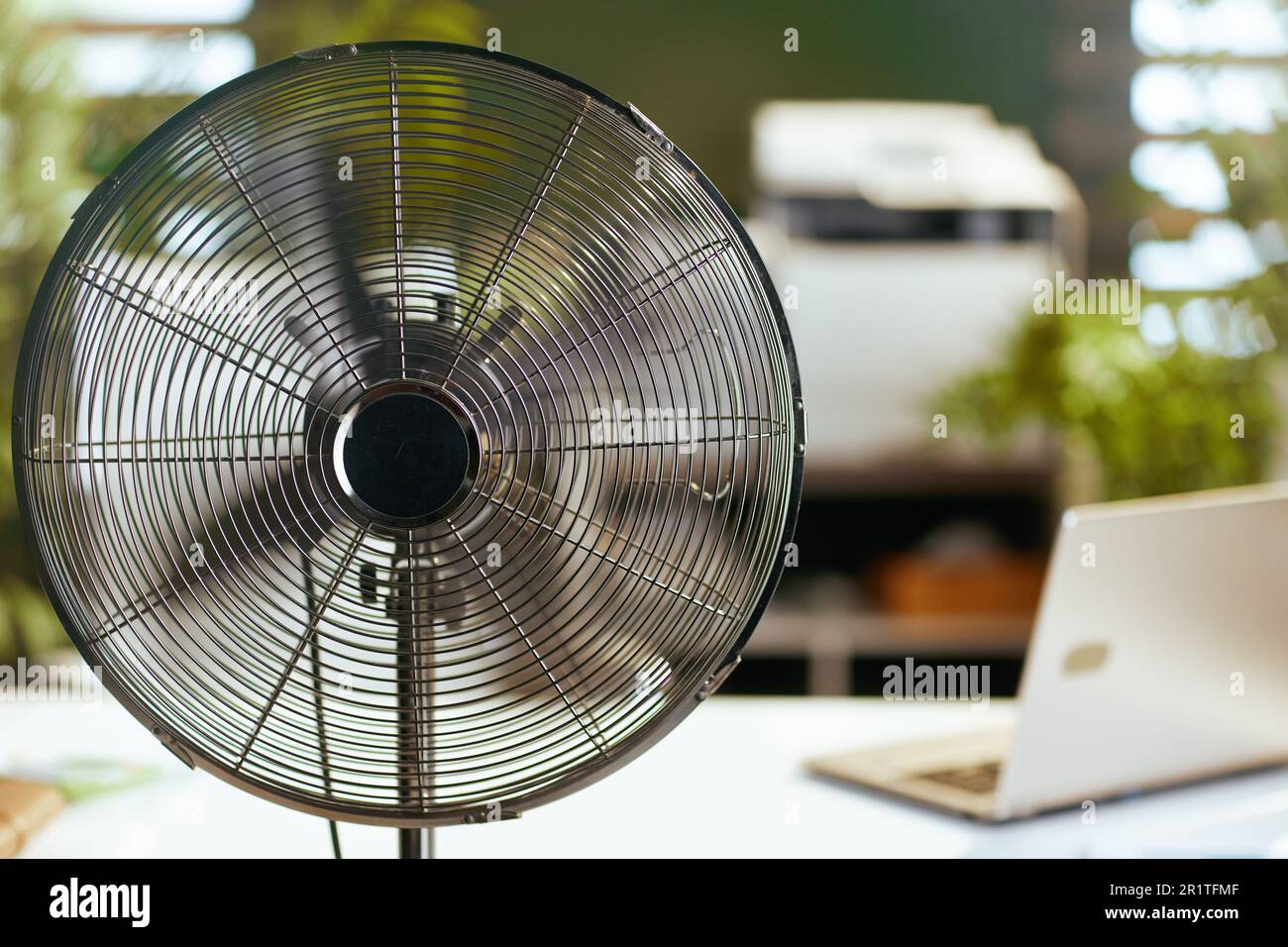Summer time. electric fan in modern green office Stock Photo - Alamy